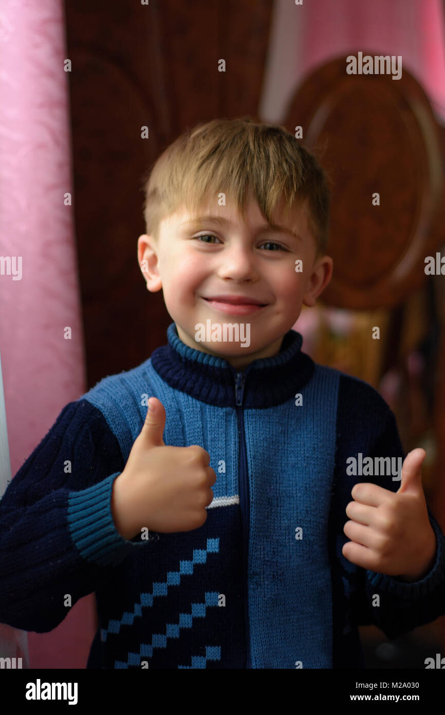 A smiling Ukrainian boy showA cute boy shows a sign ok in a blue jumper ...