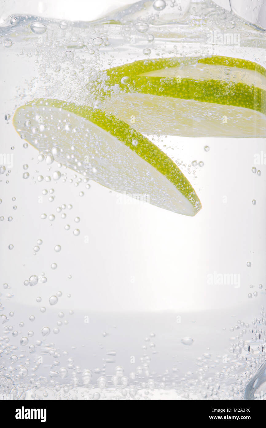 Lime slices into carbonated water with bubbles. Cold drink and refreshment close up Stock Photo ...