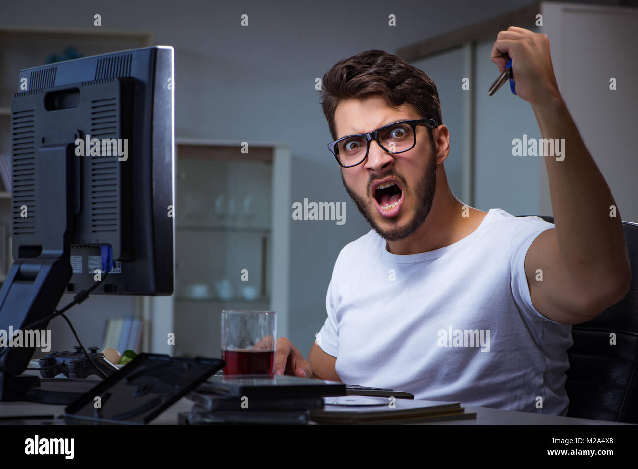 Young man staying late in office to do overtime work Stock Photo - Alamy