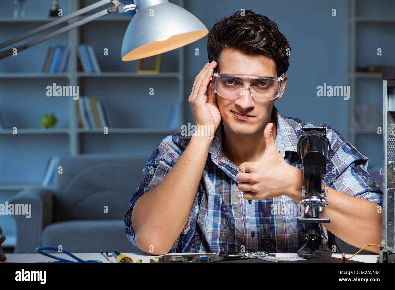 Repairman trying to repair laptop with miscroscope Stock Photo - Alamy