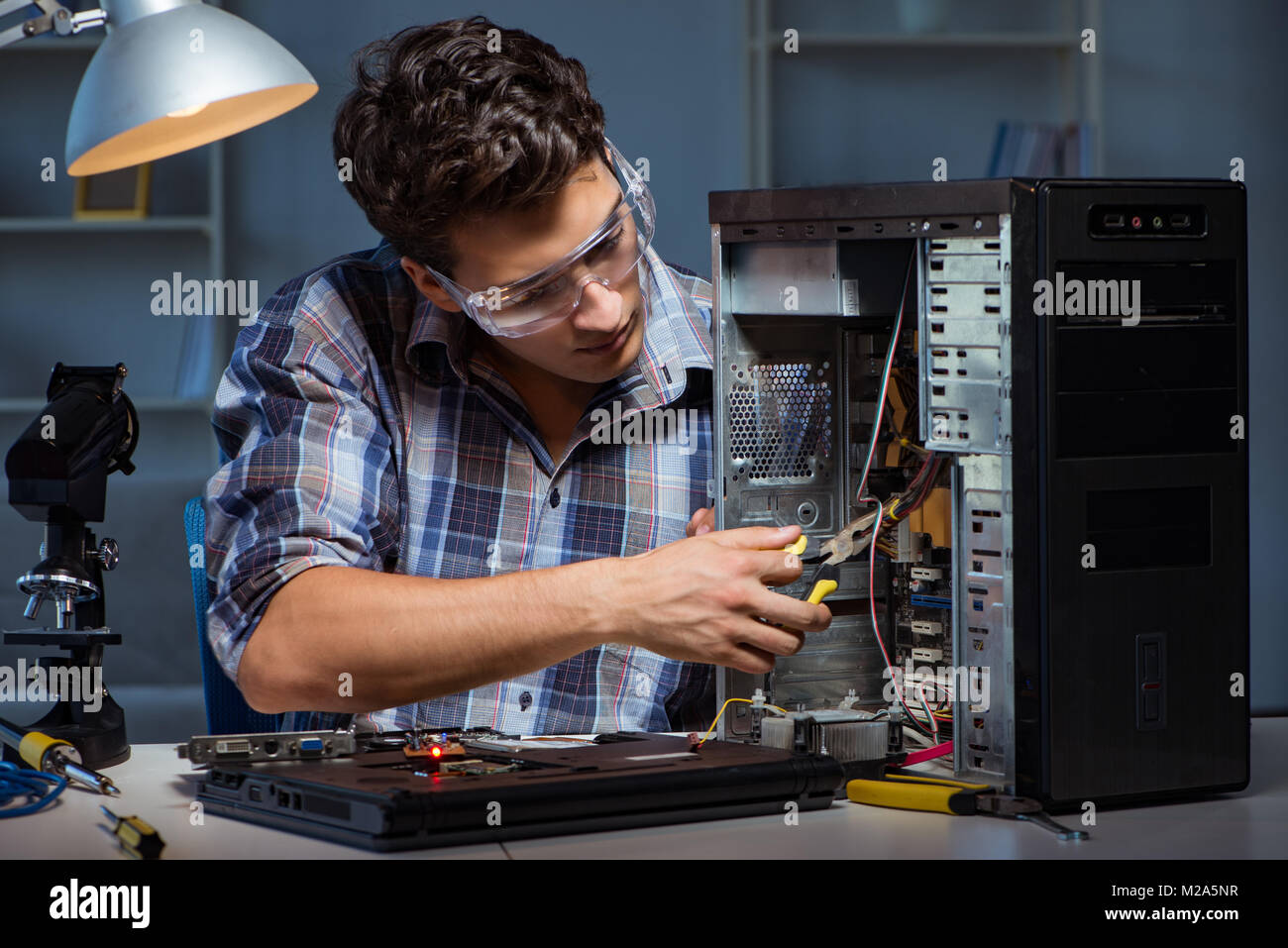 Man repairing computer desktop with pliers Stock Photo - Alamy