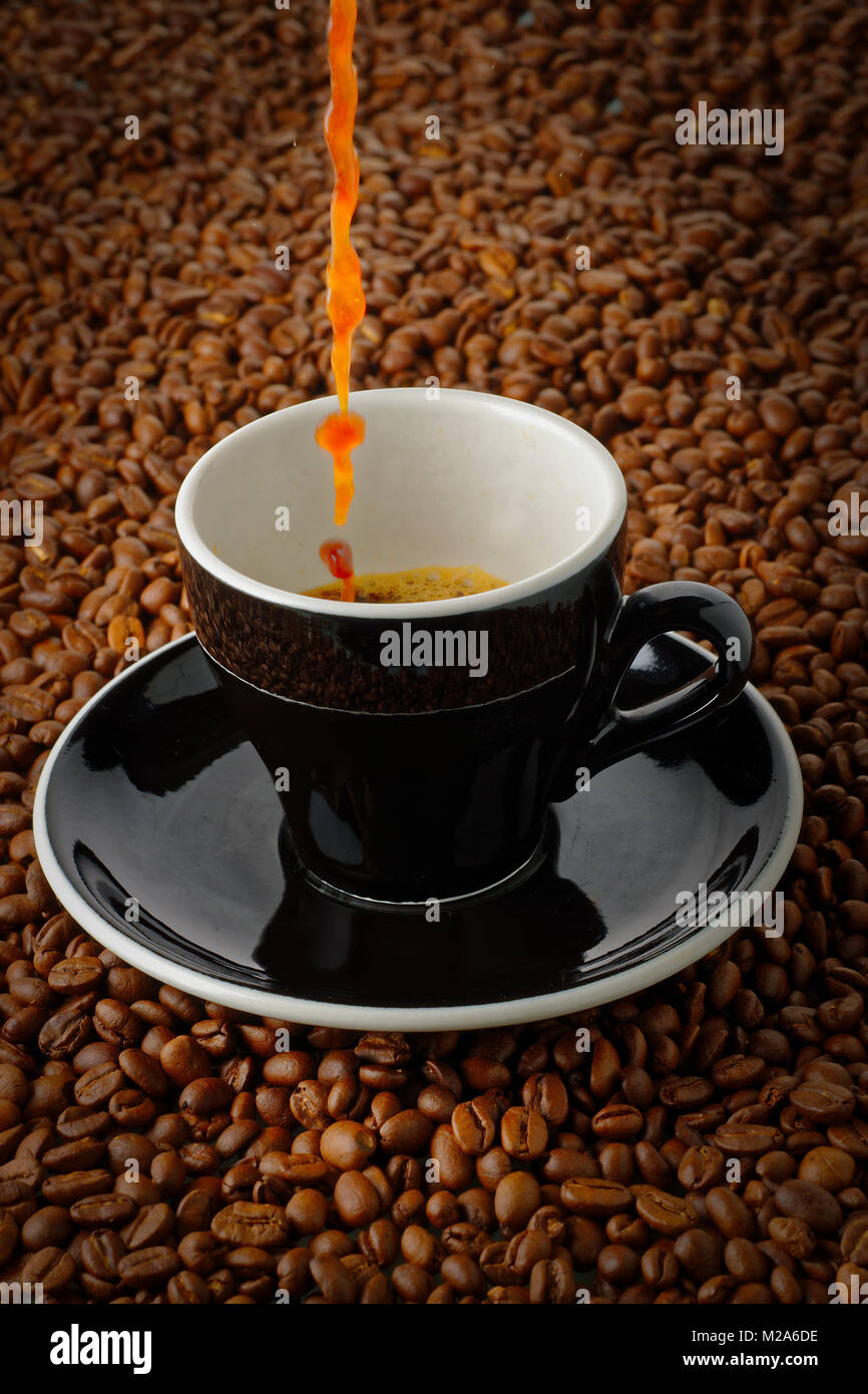 Coffee pouring down in a cup, on a bed of coffee beans Stock Photo - Alamy