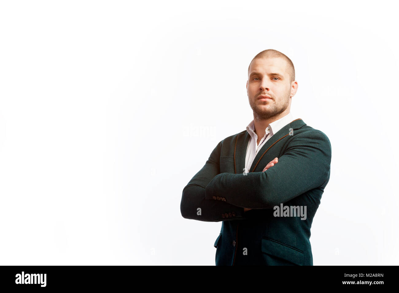 A young man manager in a white shirt, green suit looks seriously and ...