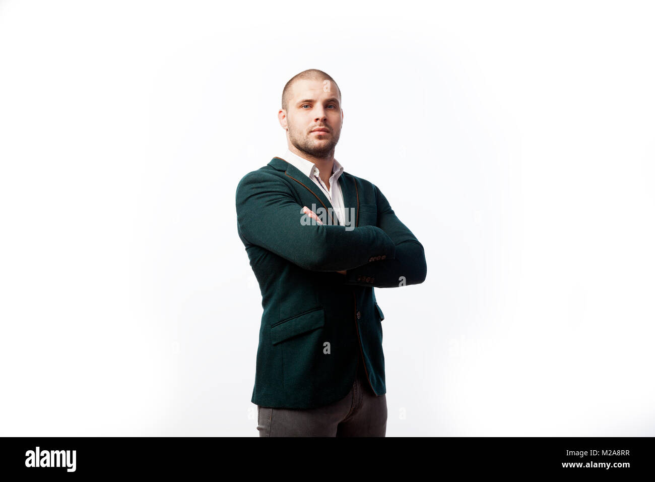 A young man manager in a white shirt, green suit looks seriously and ...