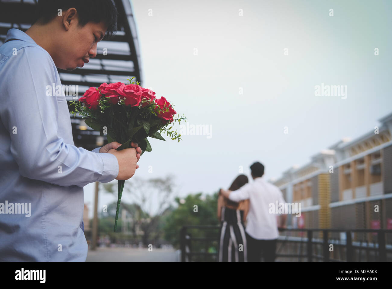 asian heartbroken man holding bouquet of red roses feeling sad while ...
