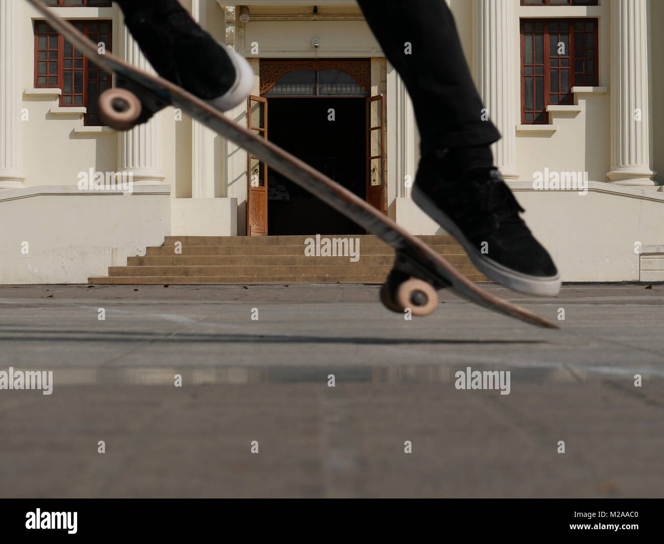 skateboarder skate & jump outdoors in front of beige building. man on ...