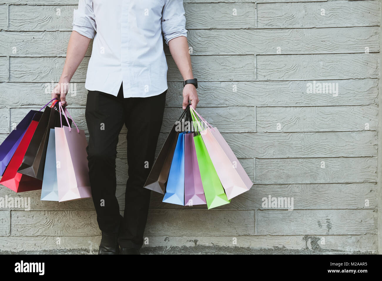 young man holding colorful shopping bag outdoors. shopaholic male ...