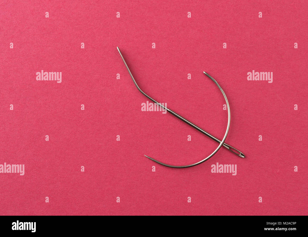 Two heavy duty upholstery cloth needles on a red paper background Stock ...