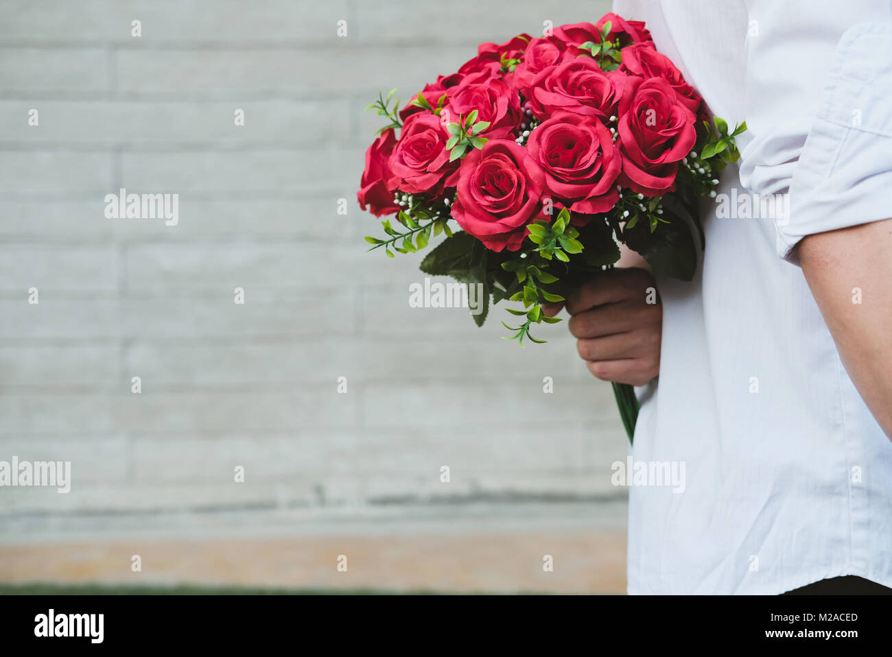 man holding bouquet of red roses behind his back. boyfriend surprise ...