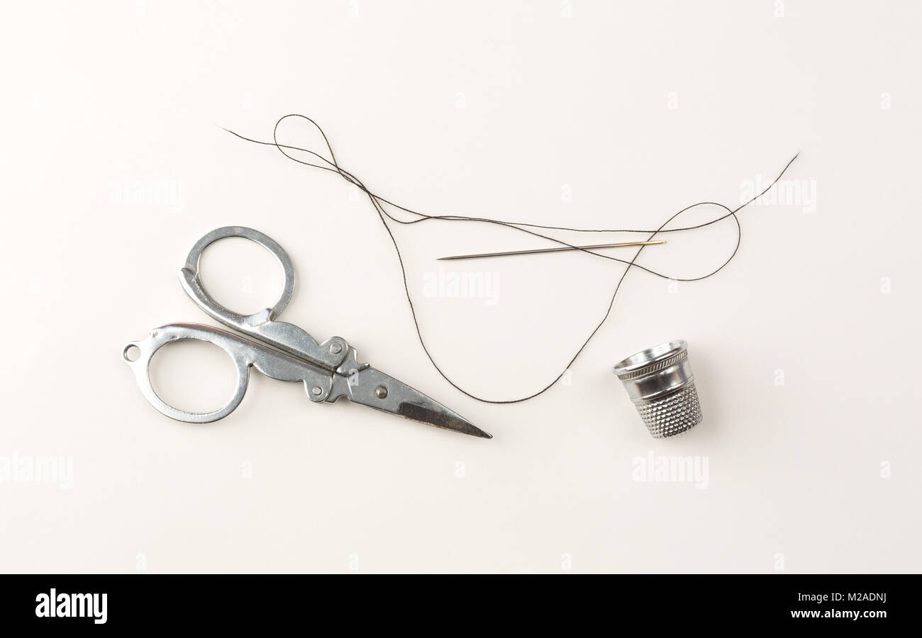An old pair of metal sewing scissors with a thimble and long threaded ...