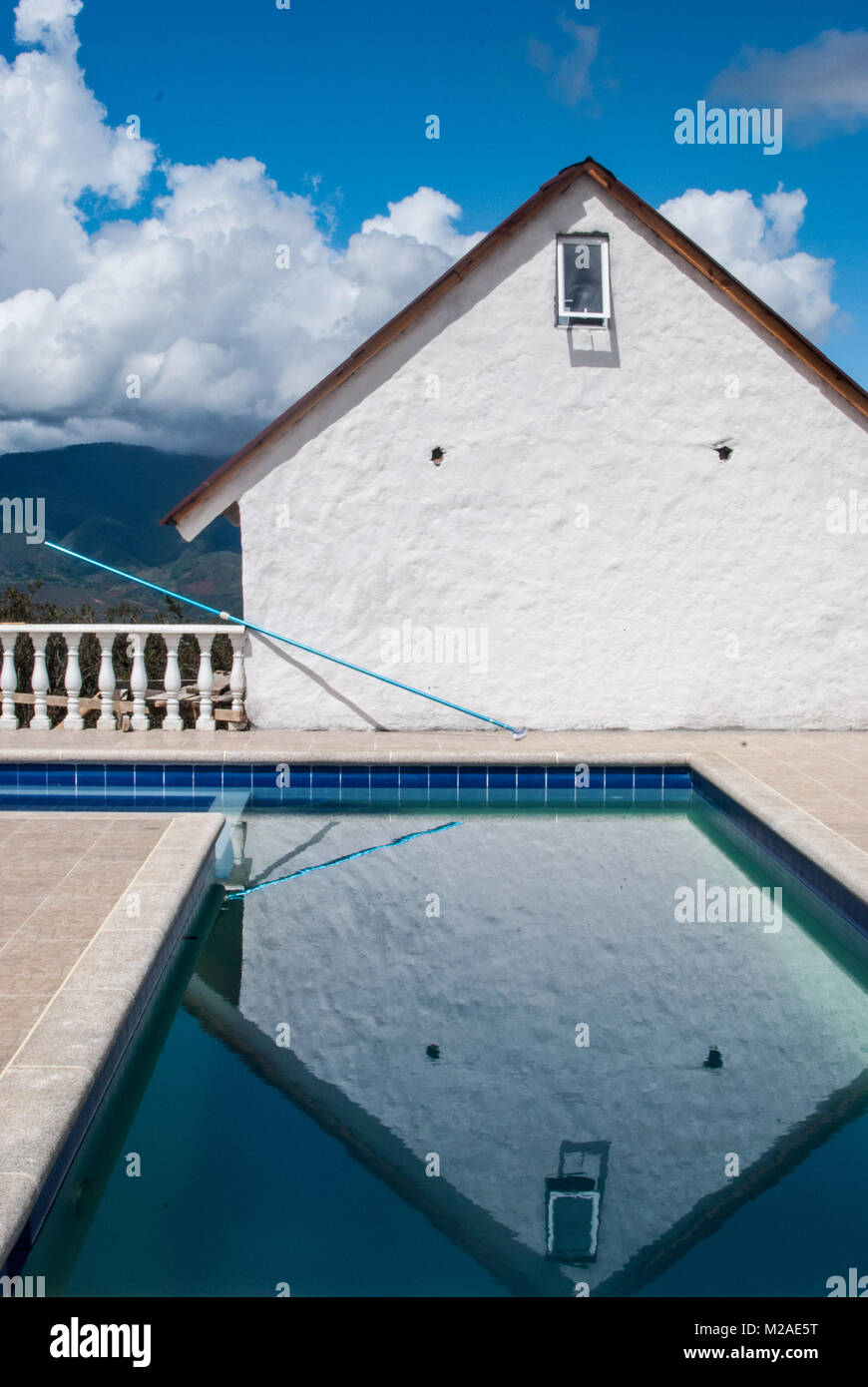 A white building reflected in a still swimming pool on a sunny day in ...