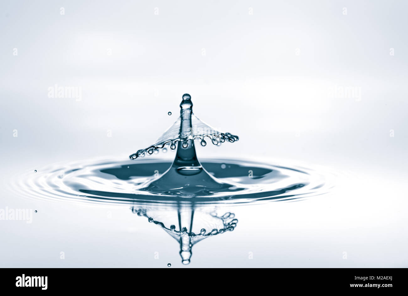 Splash and crown on rippled blue liquid or water surface . Water splash ...