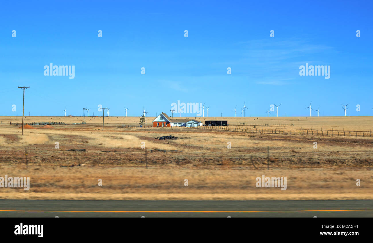 One farm house in a vast agricultural landscape with wind turbines in ...