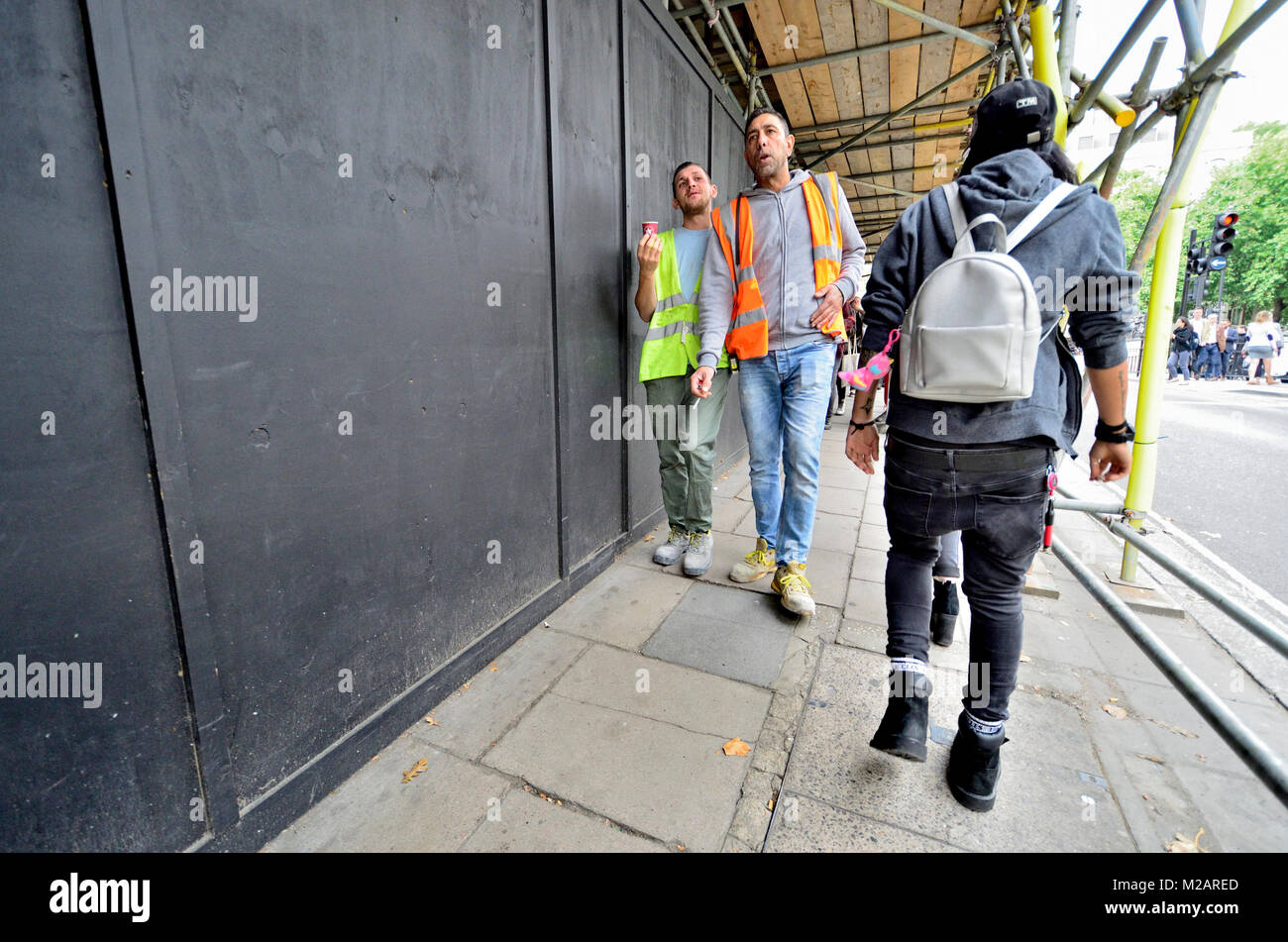 London, England, UK. Workmen in hi-vis jackets walking under ...