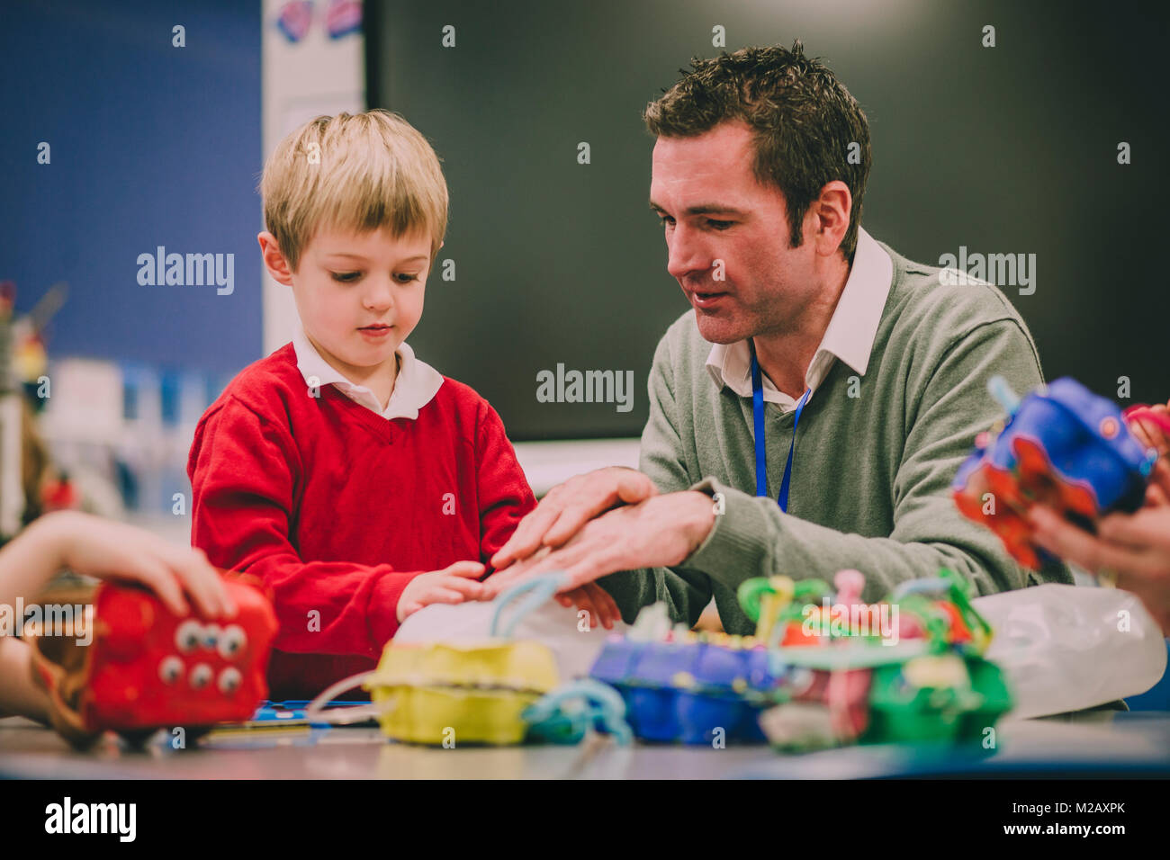 Teacher is helping his primary school student in the classroom with ...