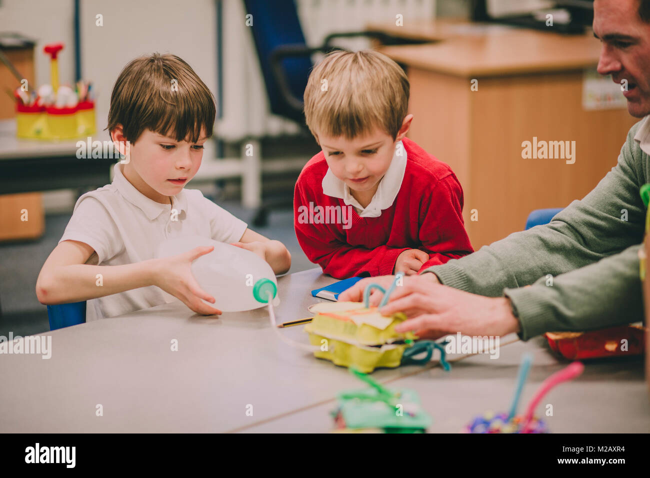 Teacher is helping his primary school students in the classroom with ...