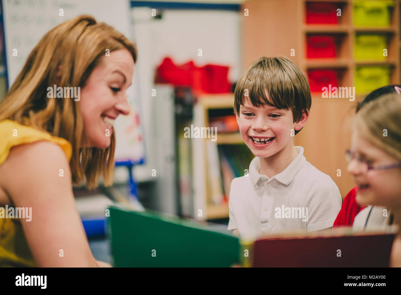 Teacher is sitting in the classroom with her primary school students ...