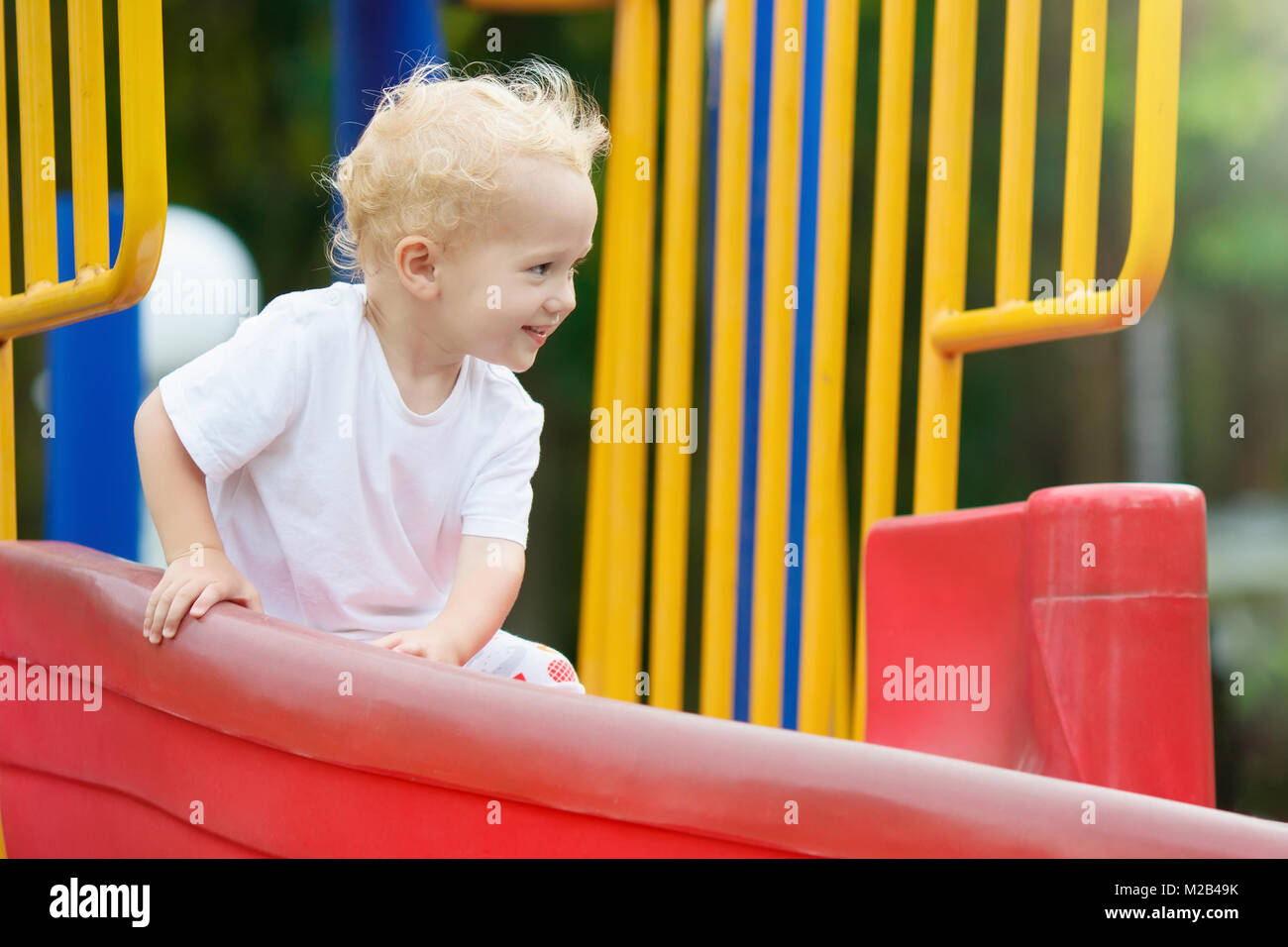 Kids climbing and sliding on outdoor playground. Children play in sunny ...