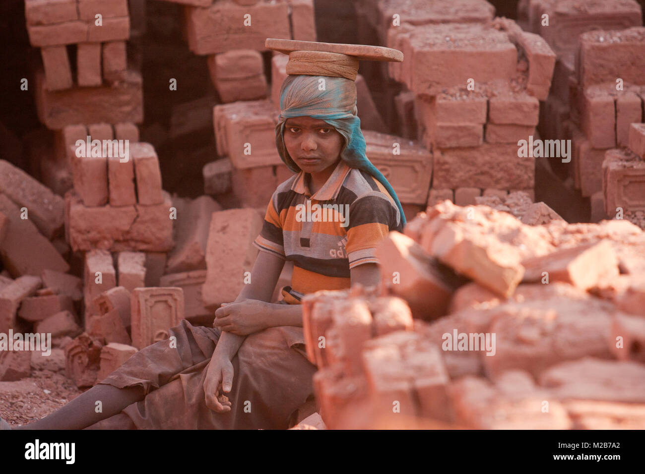 A young boy rests while carrying bricks from the kiln to the truck in ...