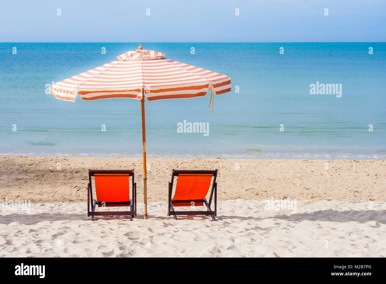 Vacation Concept : Two red wooden chairs and beach umbrella setting on ...