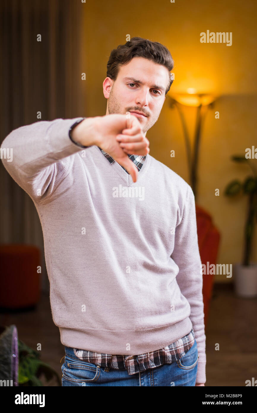 Disappointed or displeased young man doing thumb down sign Stock Photo ...