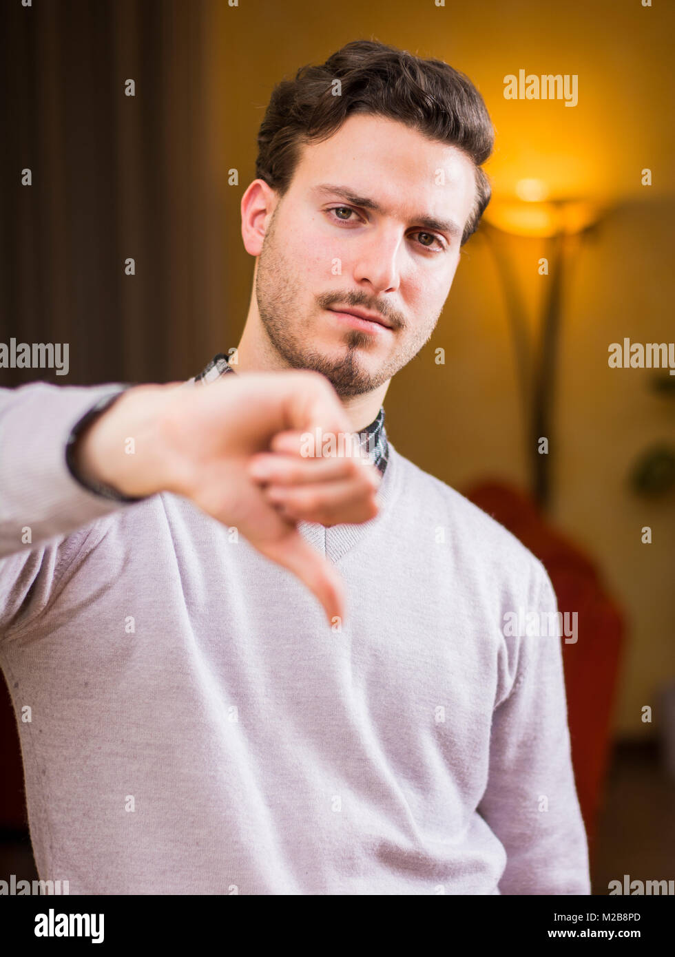 Disappointed or displeased young man doing thumb down sign Stock Photo ...