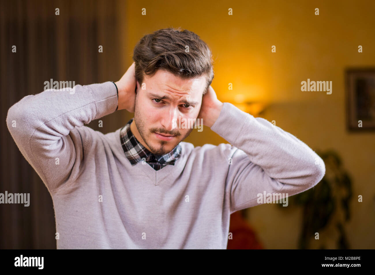 Handsome young man covering his ears, too much noise Stock Photo - Alamy