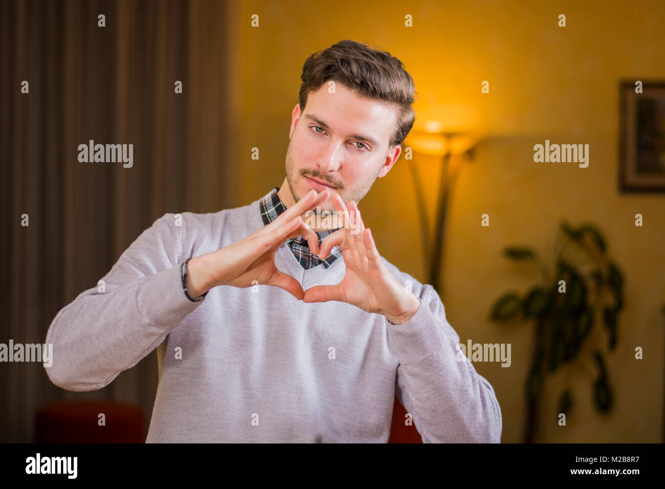 Handsome young man making heart sign with his hands Stock Photo - Alamy