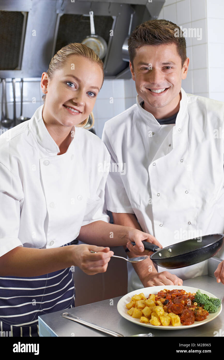 Portrait Of Chef Instructing Female Trainee In Restaurant Kitchen Stock ...