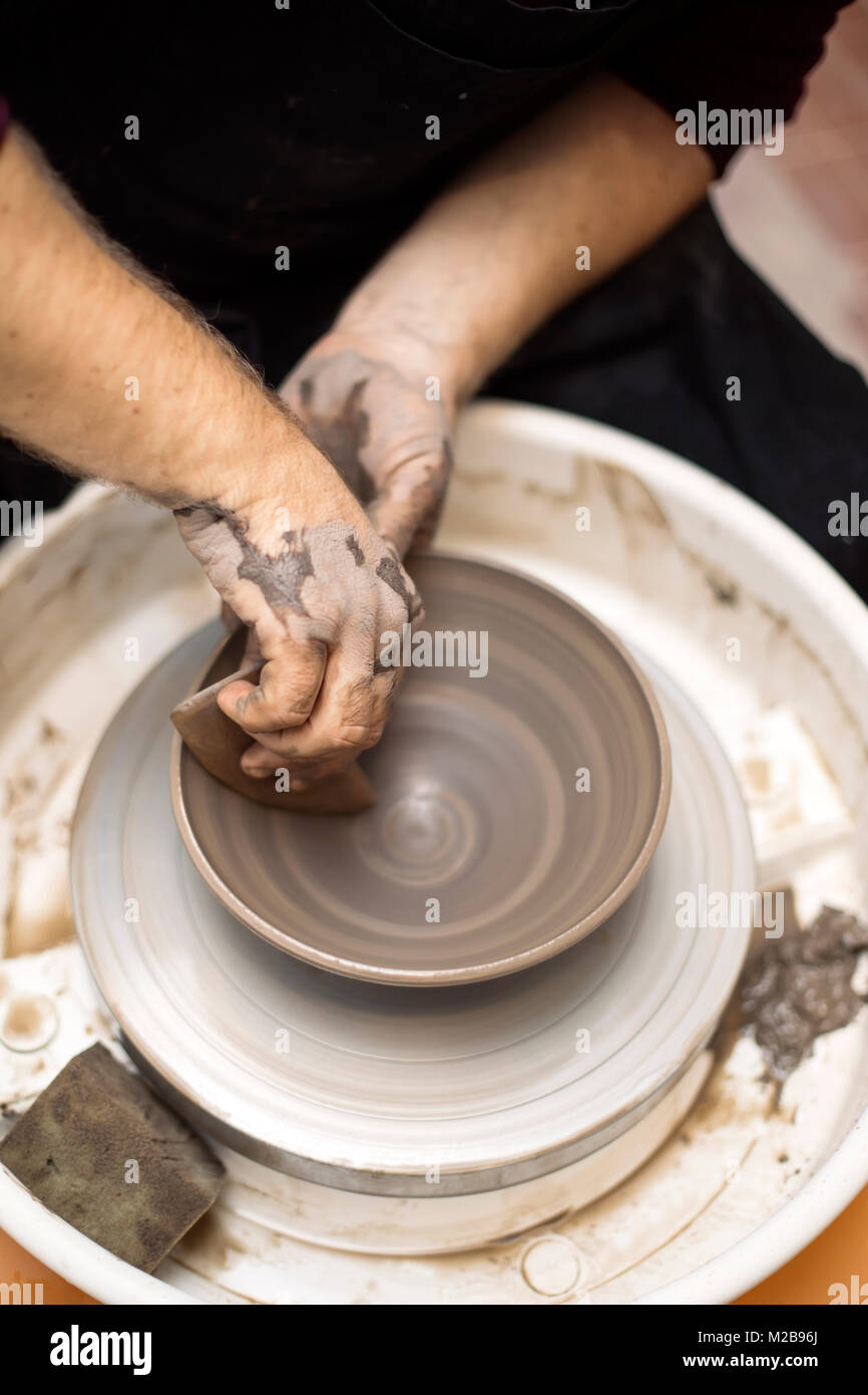 Close up detail view at an artist makes clay pottery on a spin wheel ...