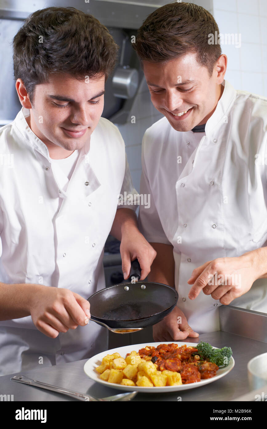 Chef Instructing Male Trainee In Restaurant Kitchen Stock Photo - Alamy