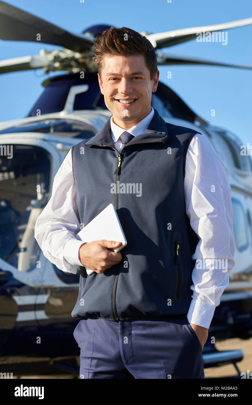Portrait Of Smiling Pilot Standing In Front Of Helicopter With Digital ...