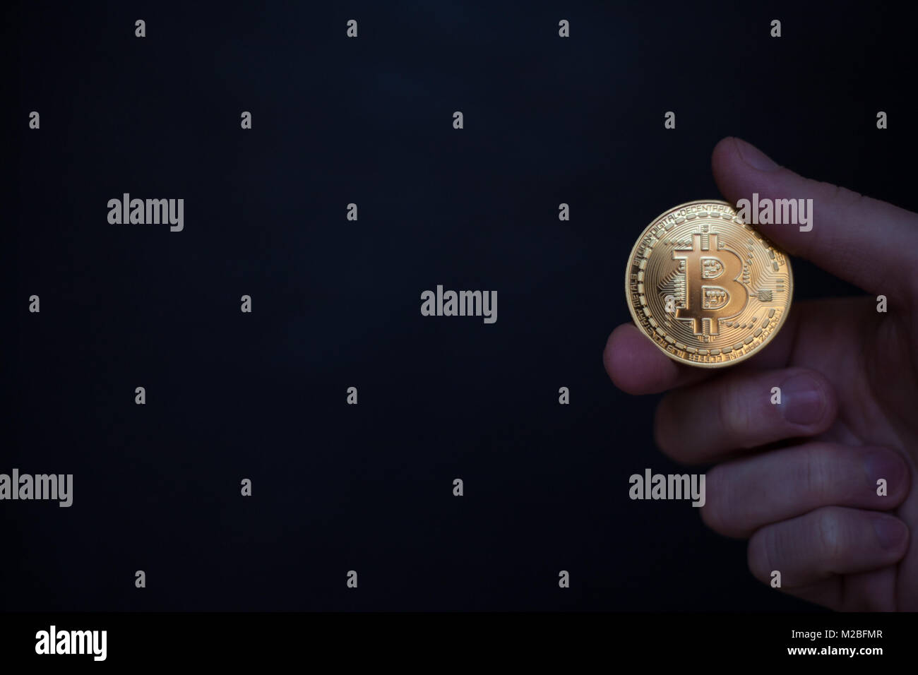 Hand holding cryptocurrency golden bitcoin isolated on dark blue ...