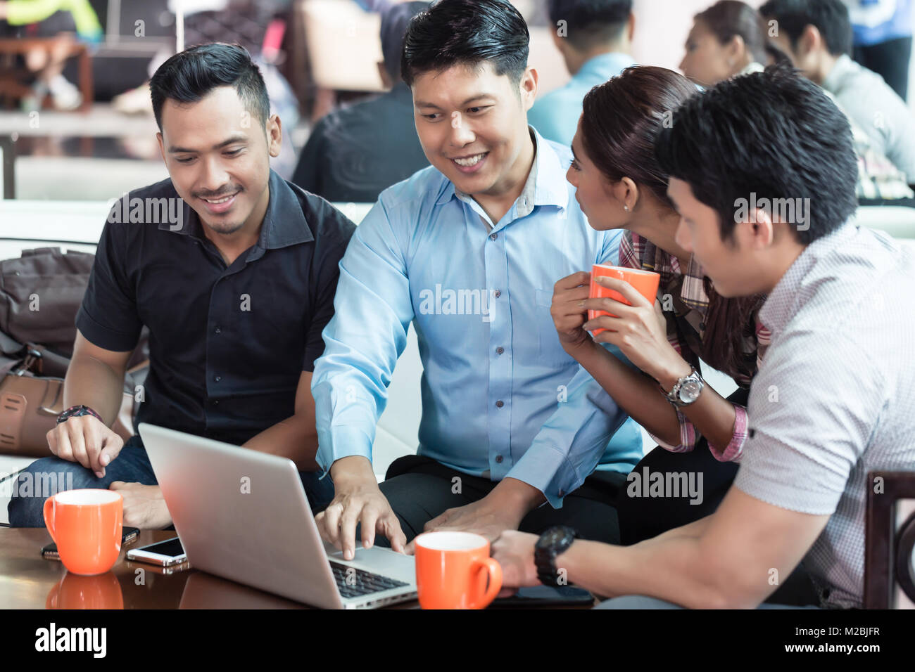 Team of four dedicated employees sitting in front of a laptop while ...