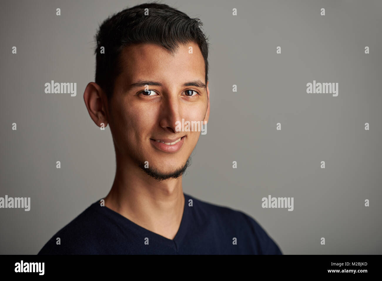 Handsome smiling young hispanic man portrait on gray background Stock ...