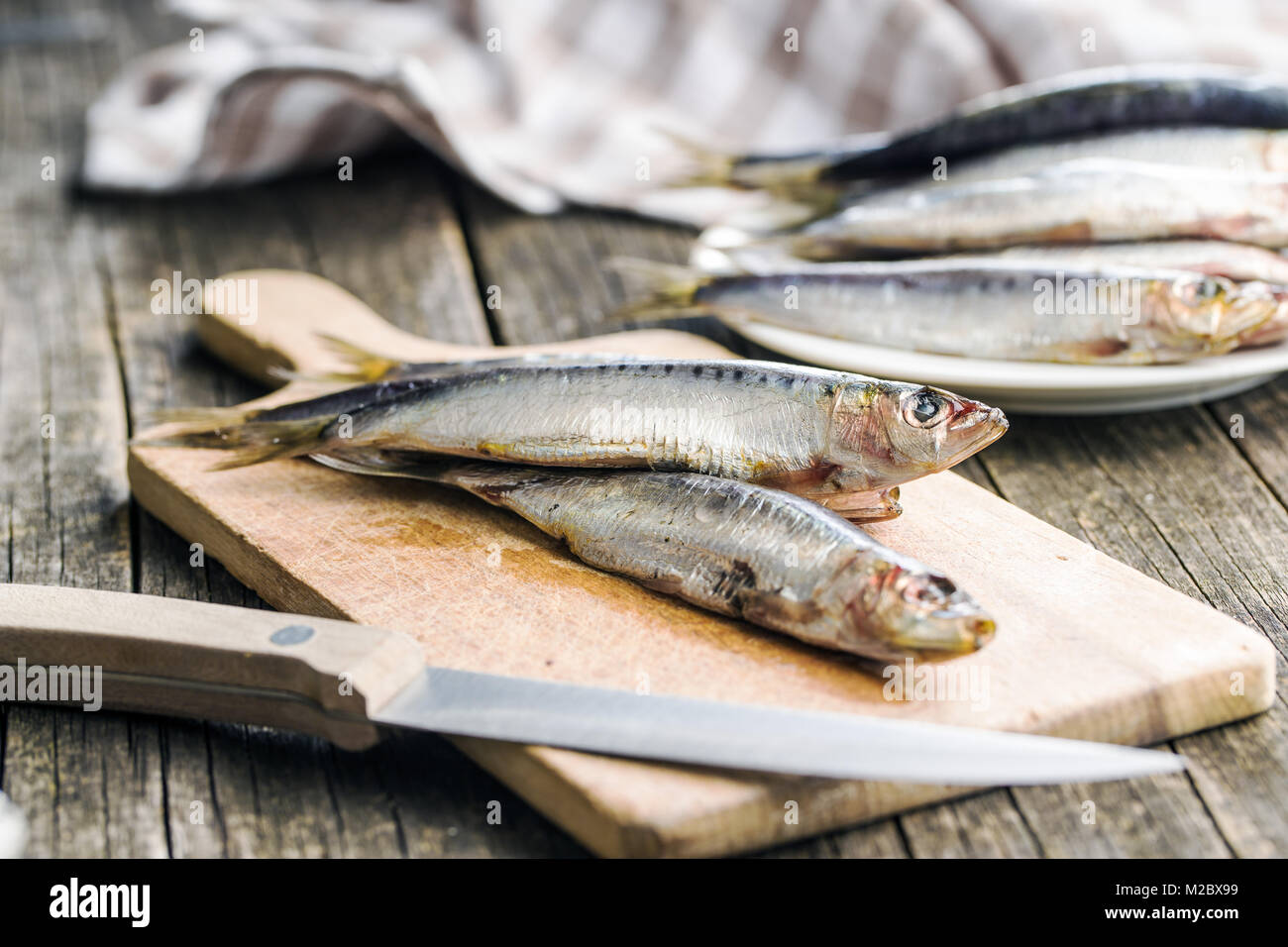 Raw sardines fish on cutting board Stock Photo - Alamy
