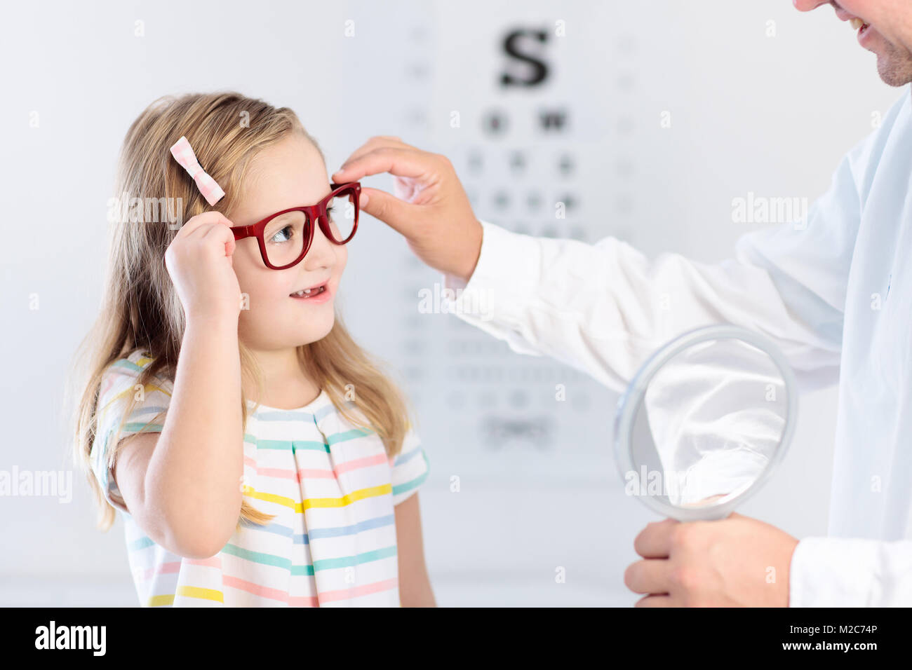 Child at eye sight test. Little kid selecting glasses at optician store ...
