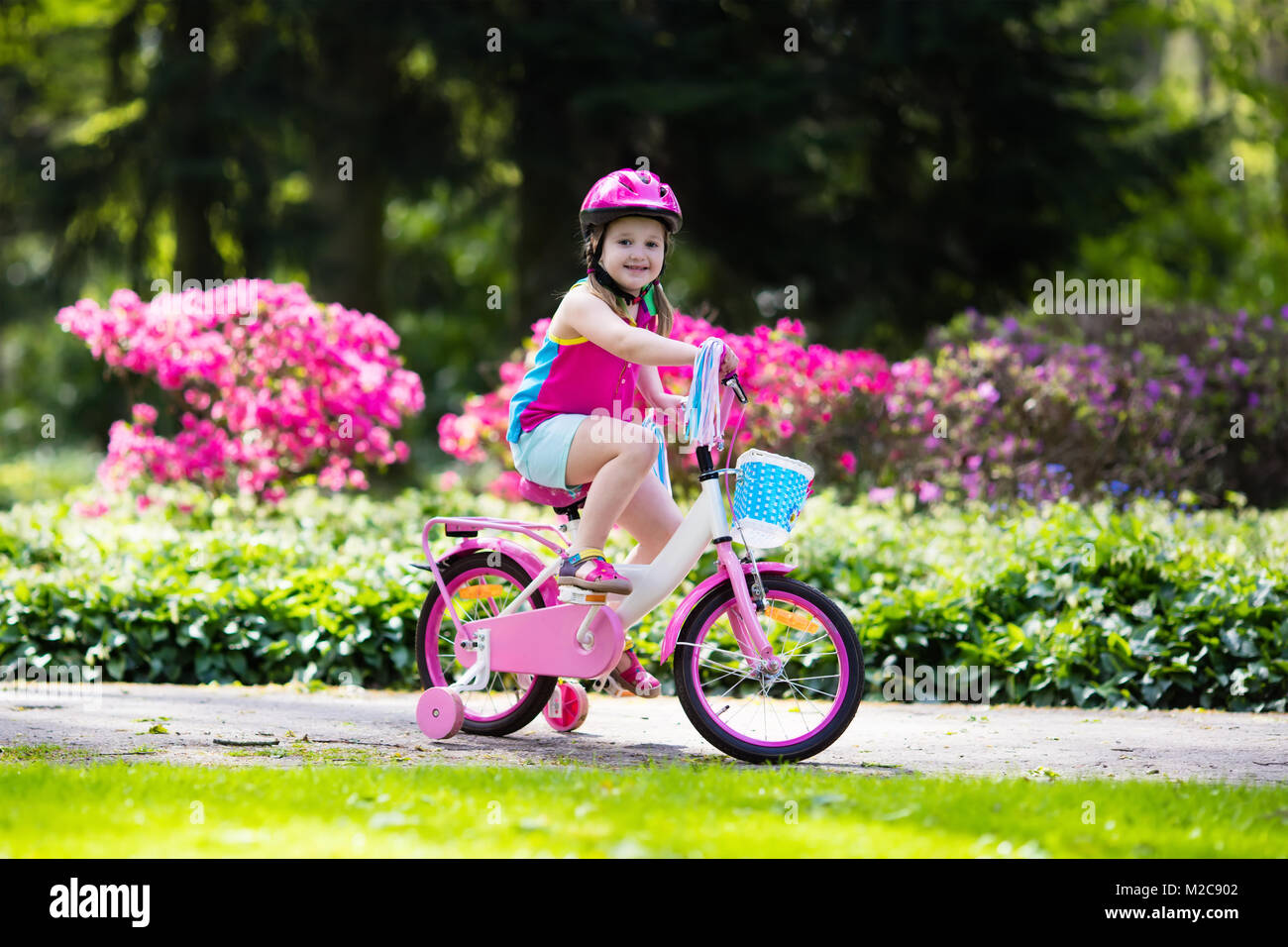 Child riding bike. Kid on bicycle in sunny park. Little girl enjoying ...