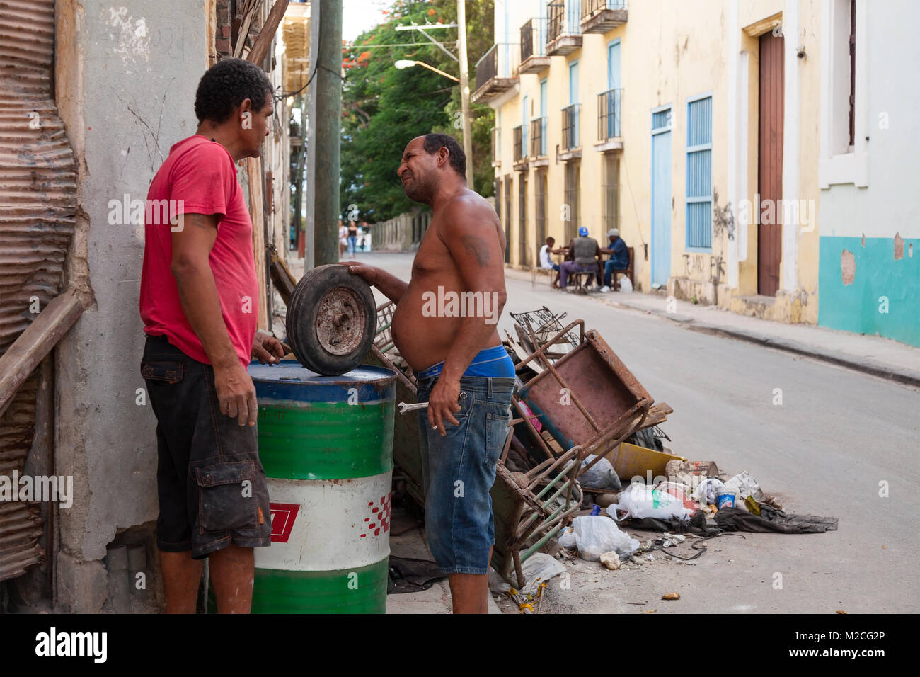 Two Cuban men and a wheel in the street in Havana, Cuba Stock Photo - Alamy