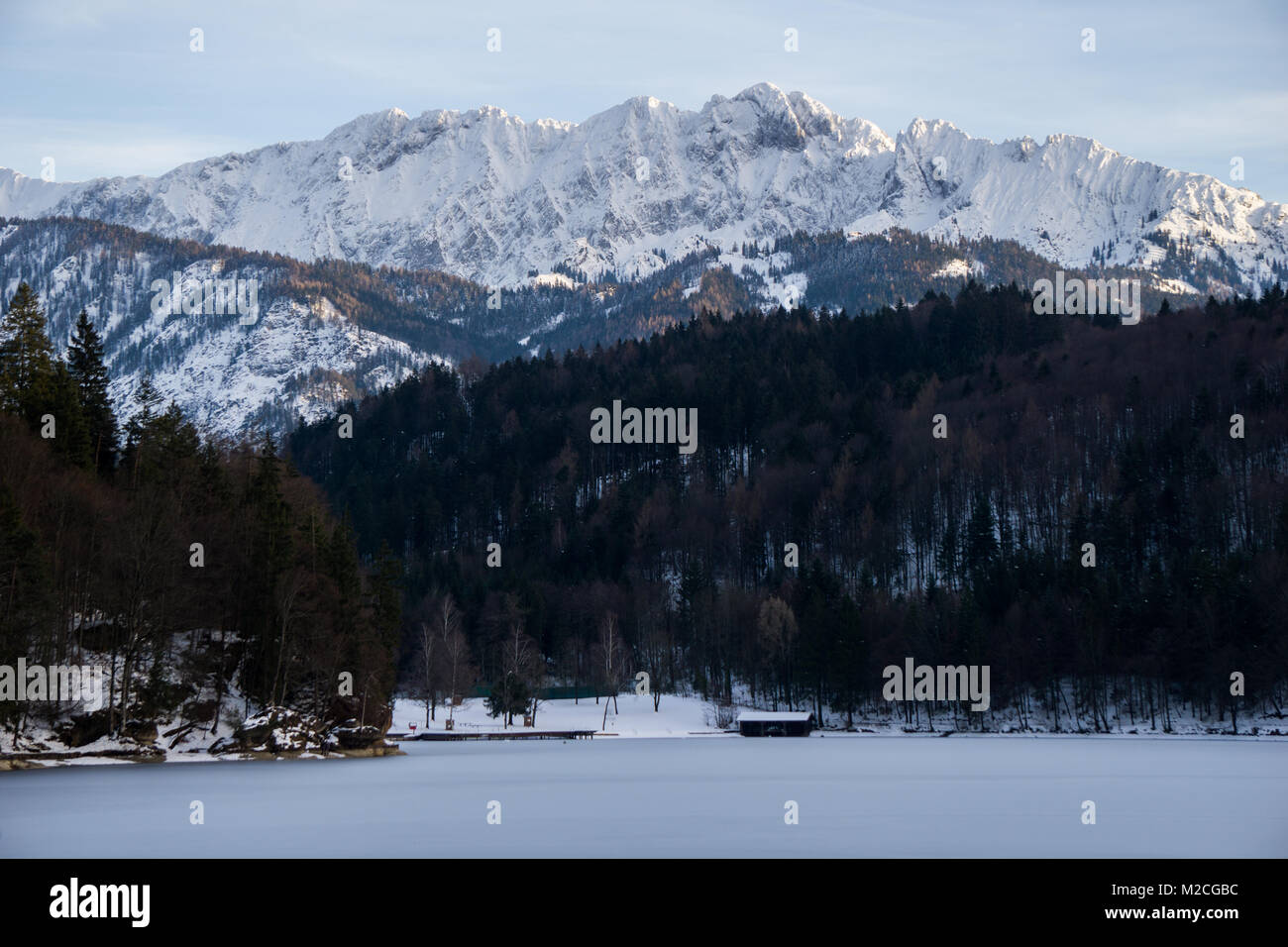 The frozen Hechtsee lake with the massive Wilder Kaiser Alps rising in ...