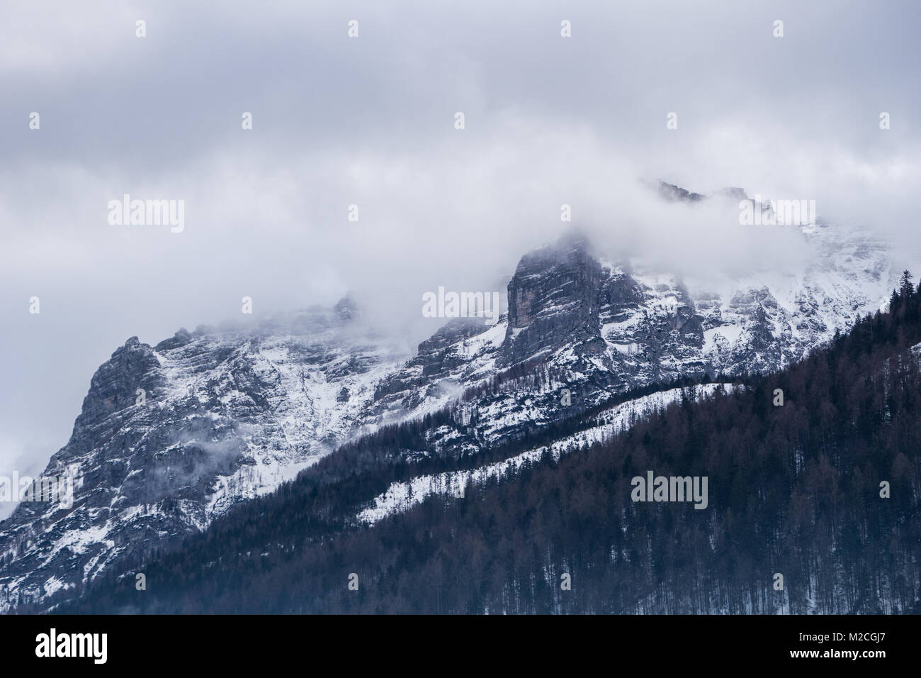 Dramatic alpine scenery with fog and clouds shrouding the mountain top ...