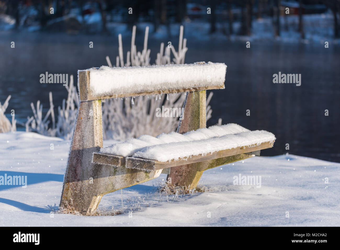 a cold and frozen bench covered in snow in sweden Stock Photo - Alamy