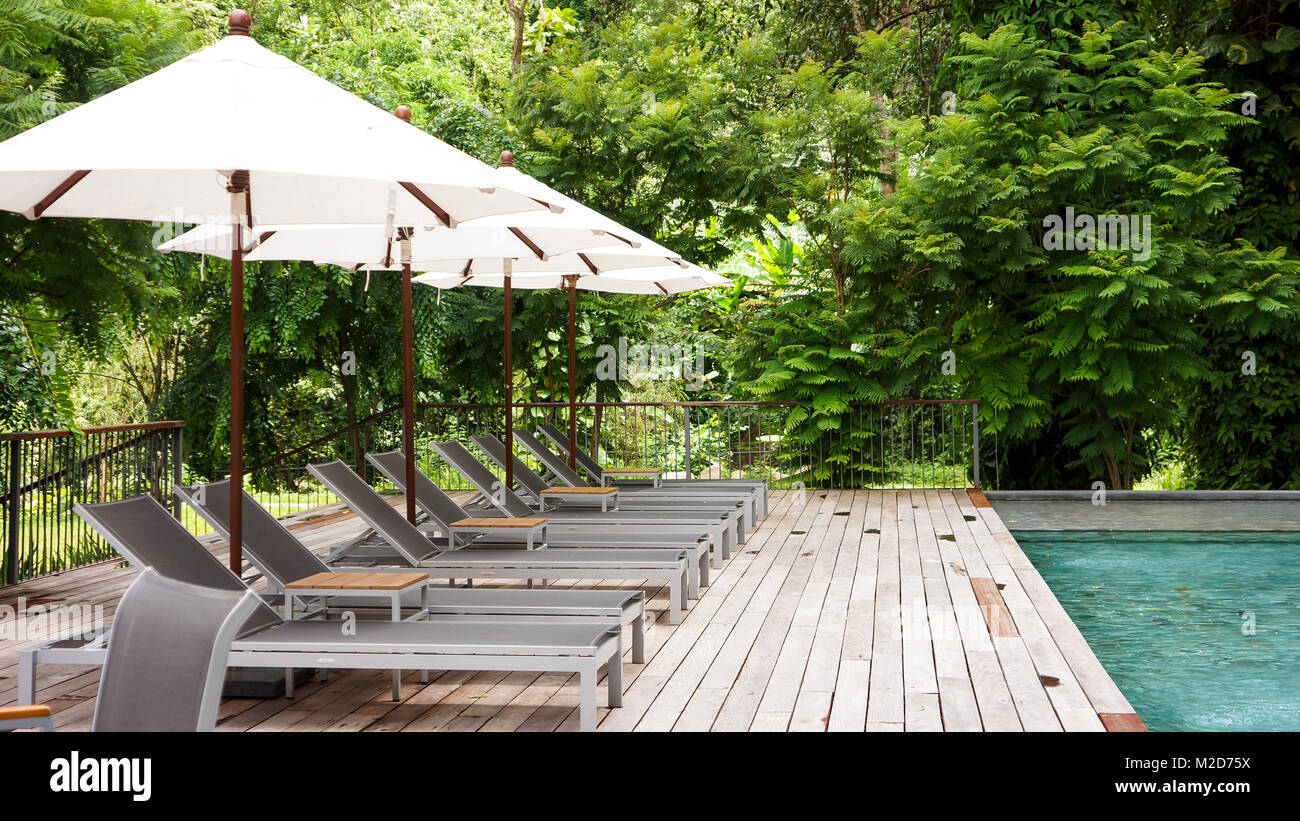 Empty poolside loungers with umbrellas Stock Photo - Alamy