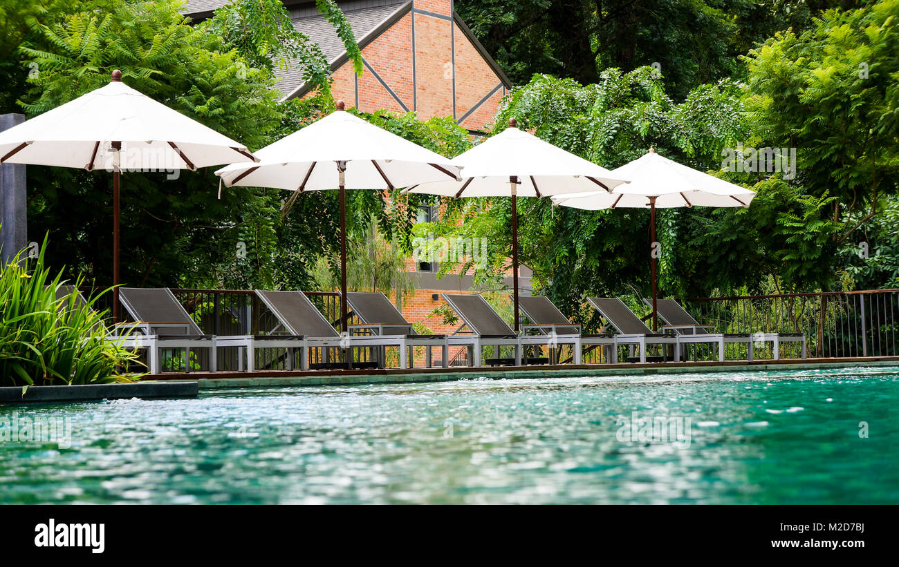 Empty poolside loungers with umbrellas Stock Photo - Alamy
