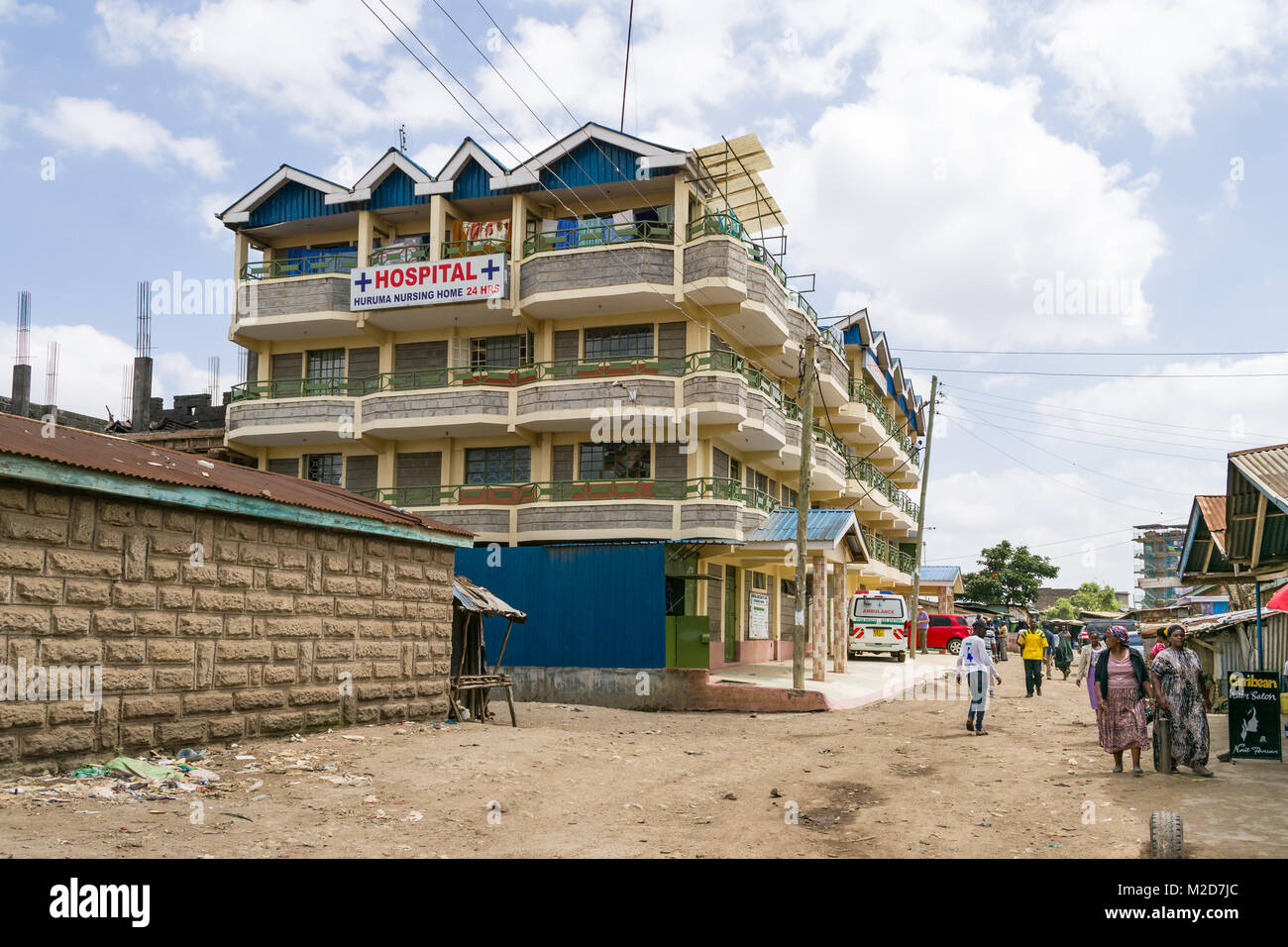 The exterior of a hospital in Huruma with people walking past on a ...