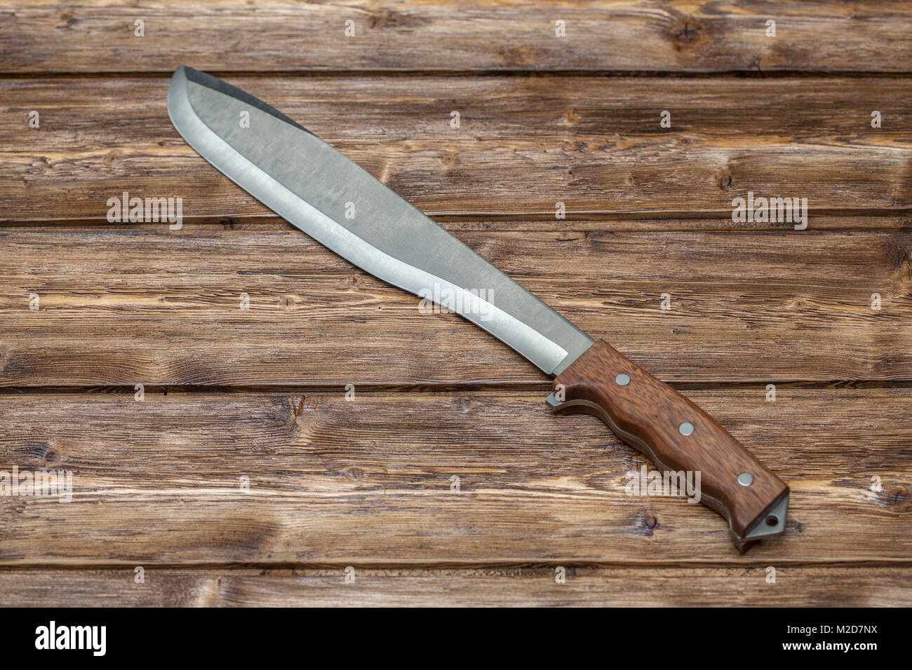 Machete for cutting grass on brown wooden background Stock Photo - Alamy
