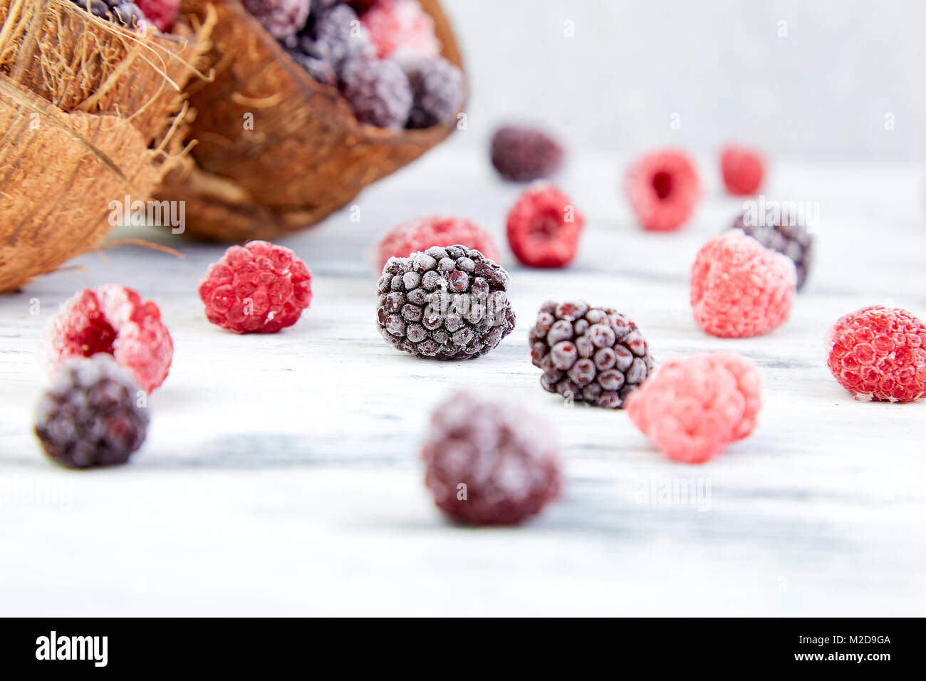 Frozen black and red raspberries in coconut bowl Stock Photo - Alamy