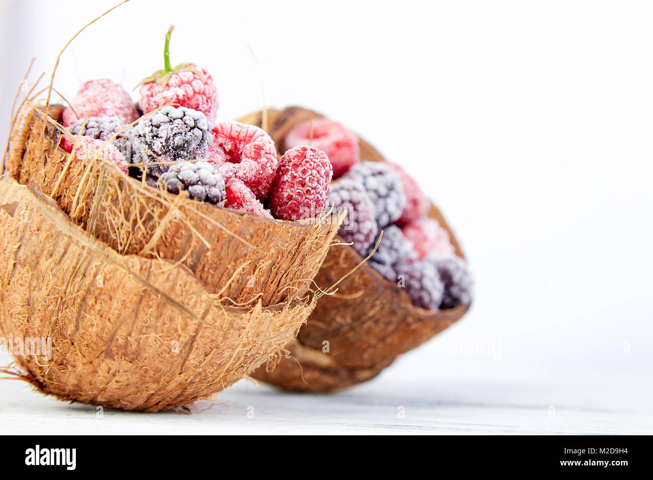 Frozen black and red raspberries in coconut bowl Stock Photo - Alamy