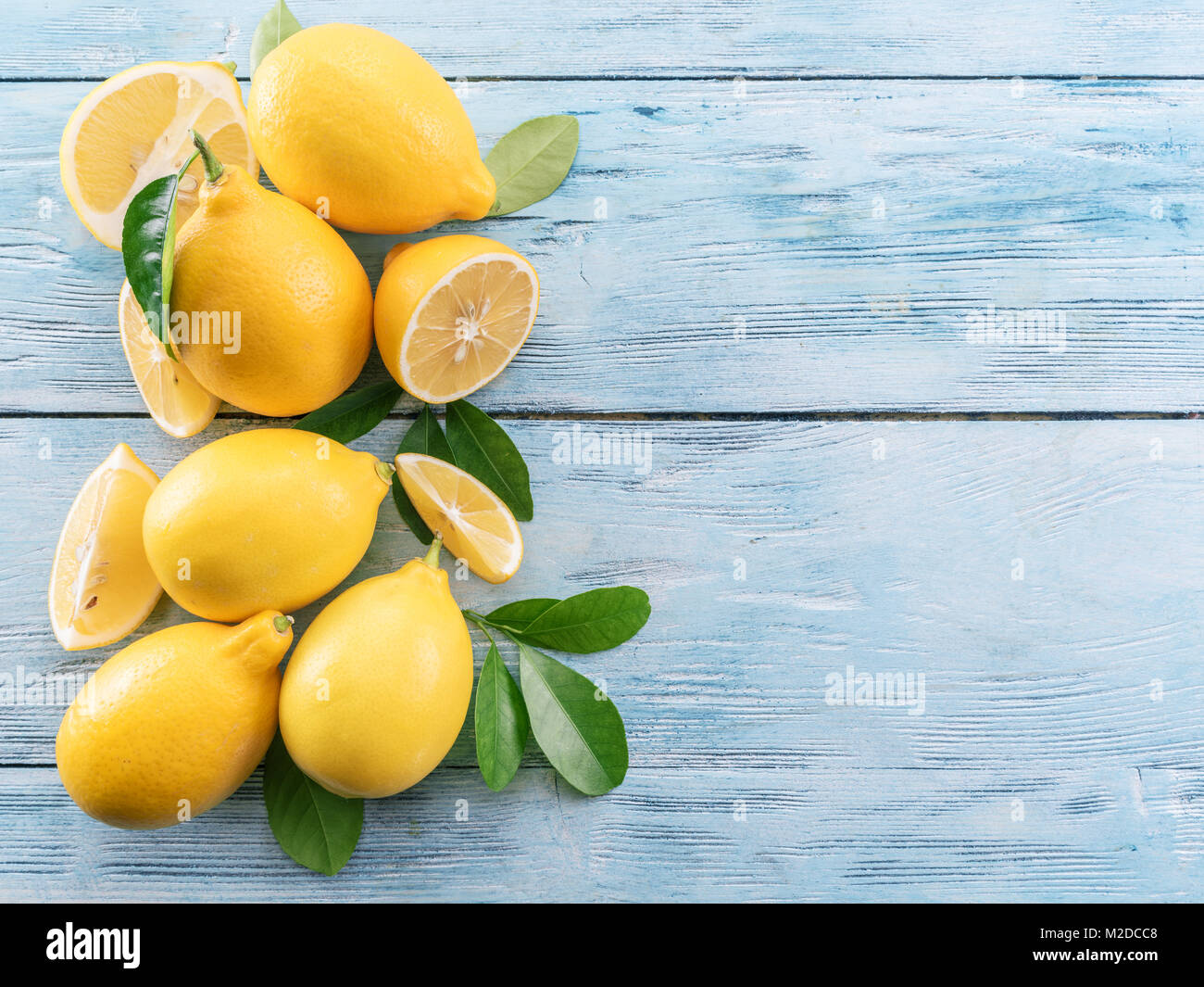 Ripe lemons and lemon leaves on blue wooden background. Top view Stock ...