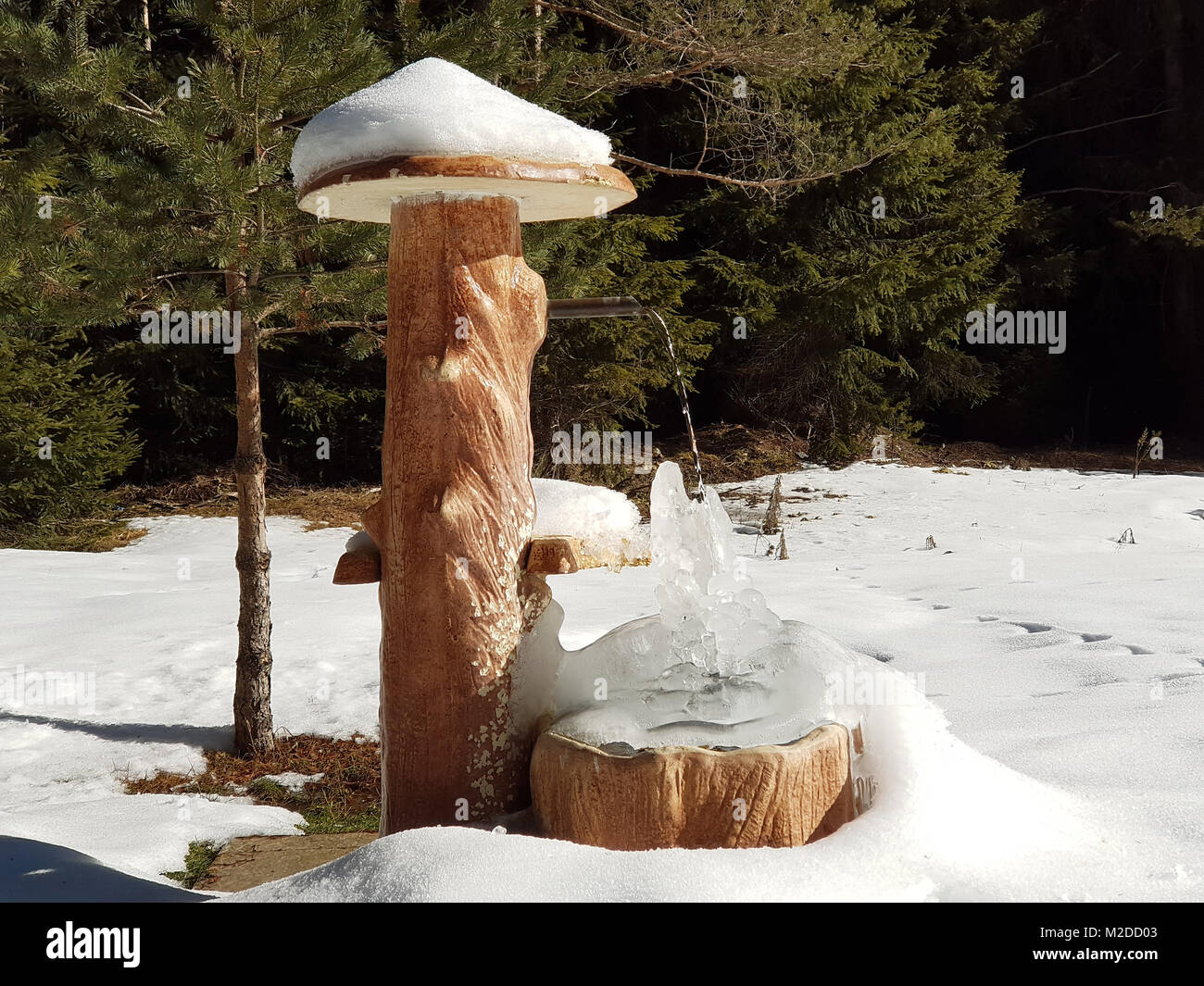 Frozen fountain with a cold mountain drinkable water under snow and ice ...